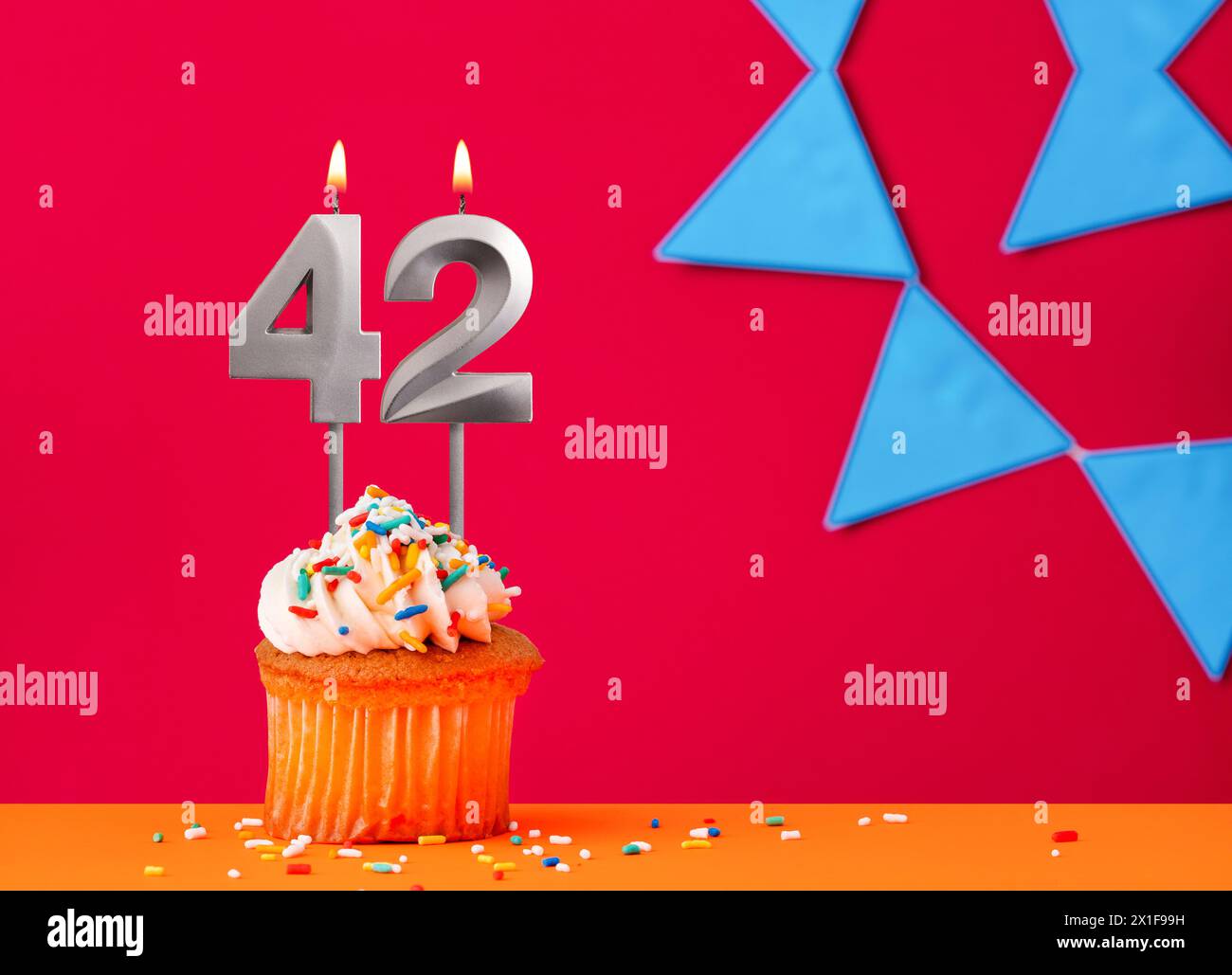 Birthday cupcake with candle number 42 on a red background with blue ...