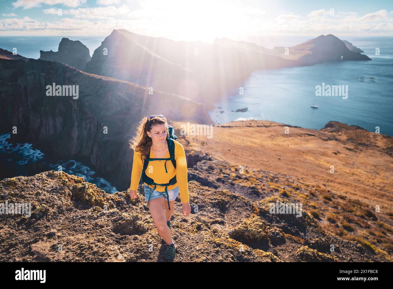 Description: Front view of a tourist backpacker walking up foothills of ...
