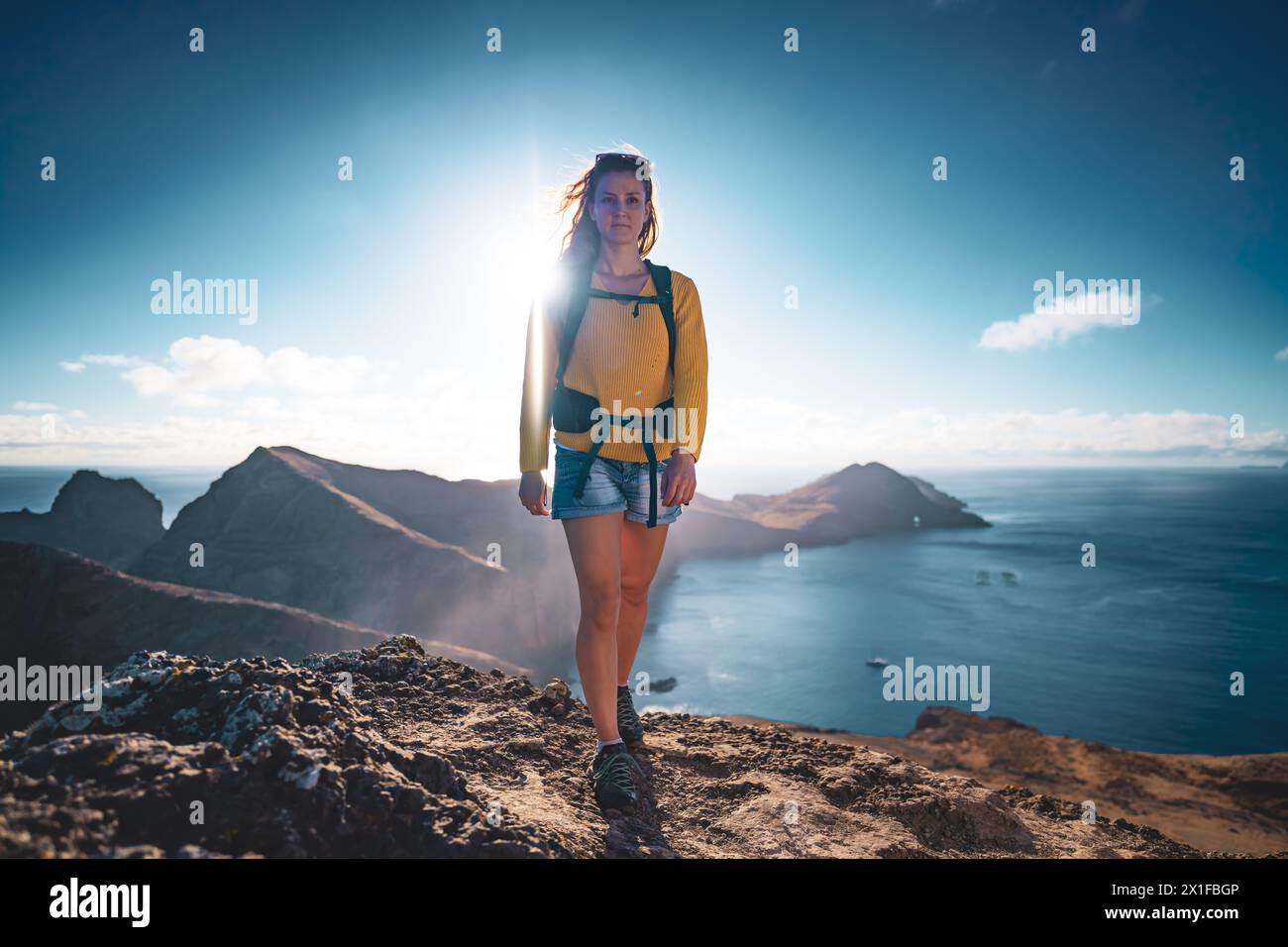 Description: Low angle front view of a female backpacker walking on top ...