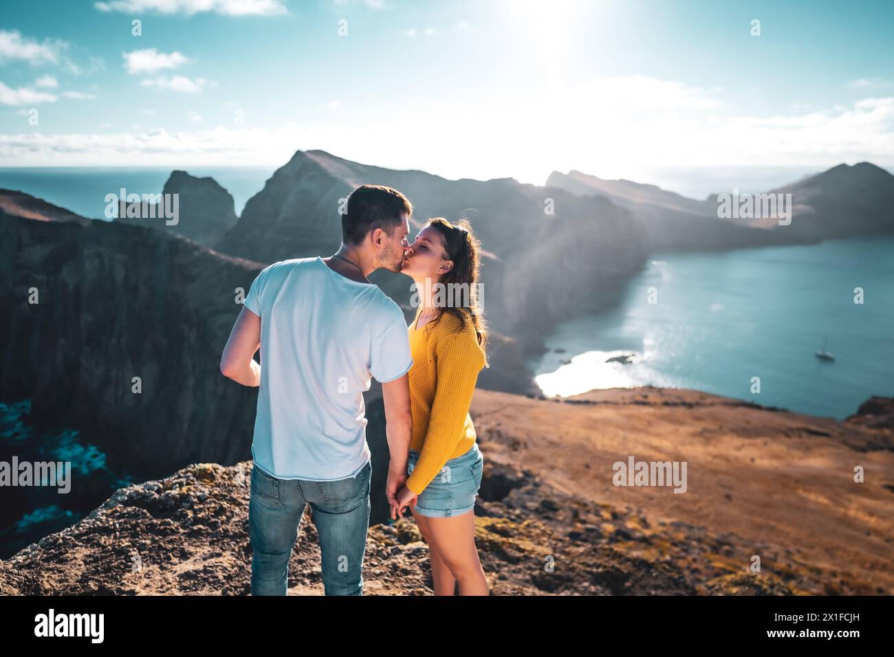 Description: Back view of a kissing touist couple, enjoying the coastal ...