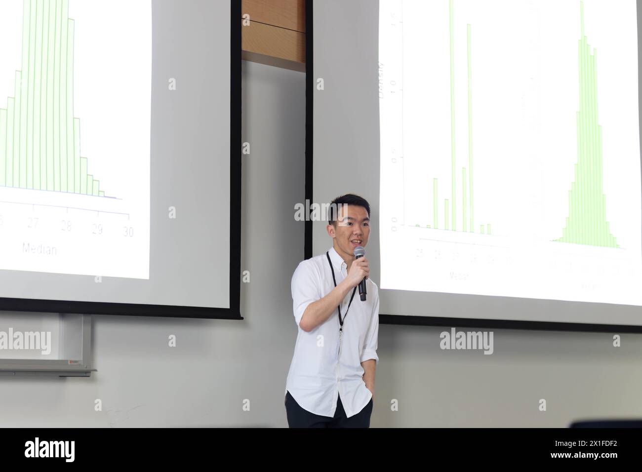 Young man presenting in front of a projection screen with bar chart ...