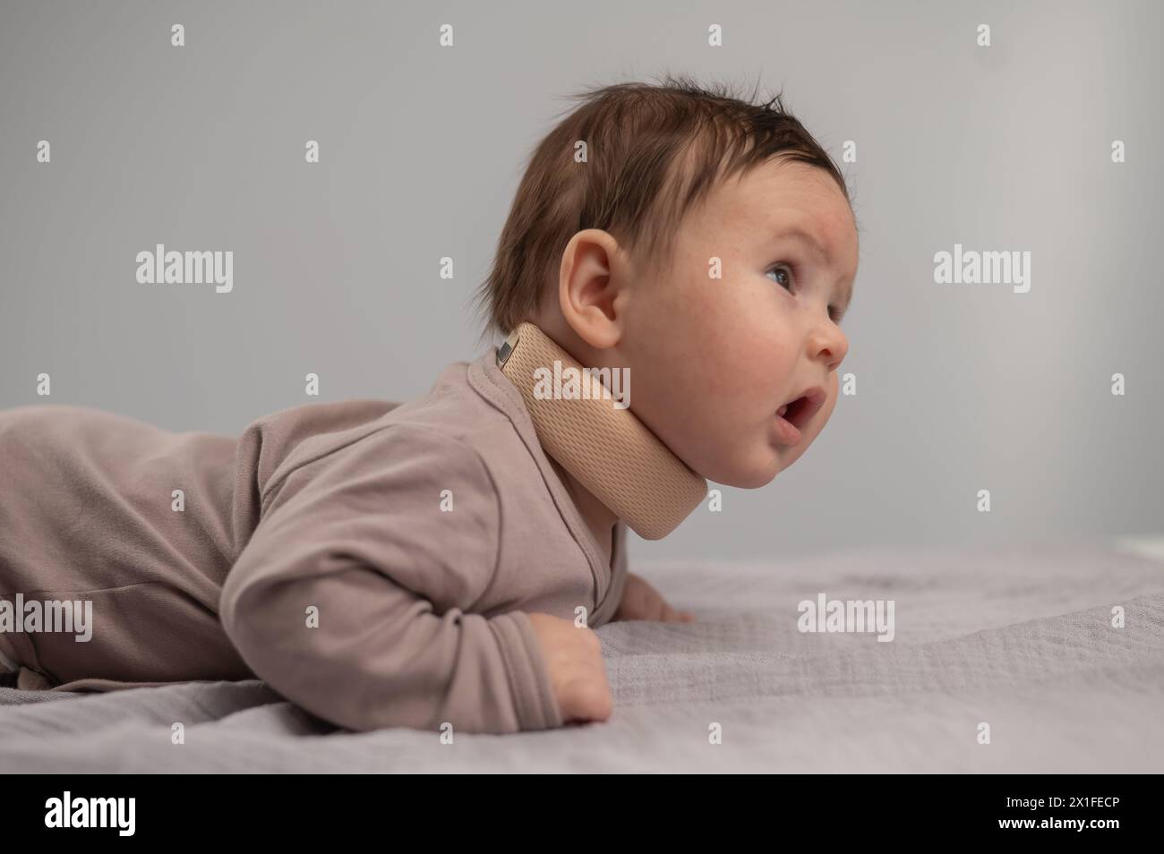Portrait of a newborn baby lying on his stomach in an orthopedic collar ...