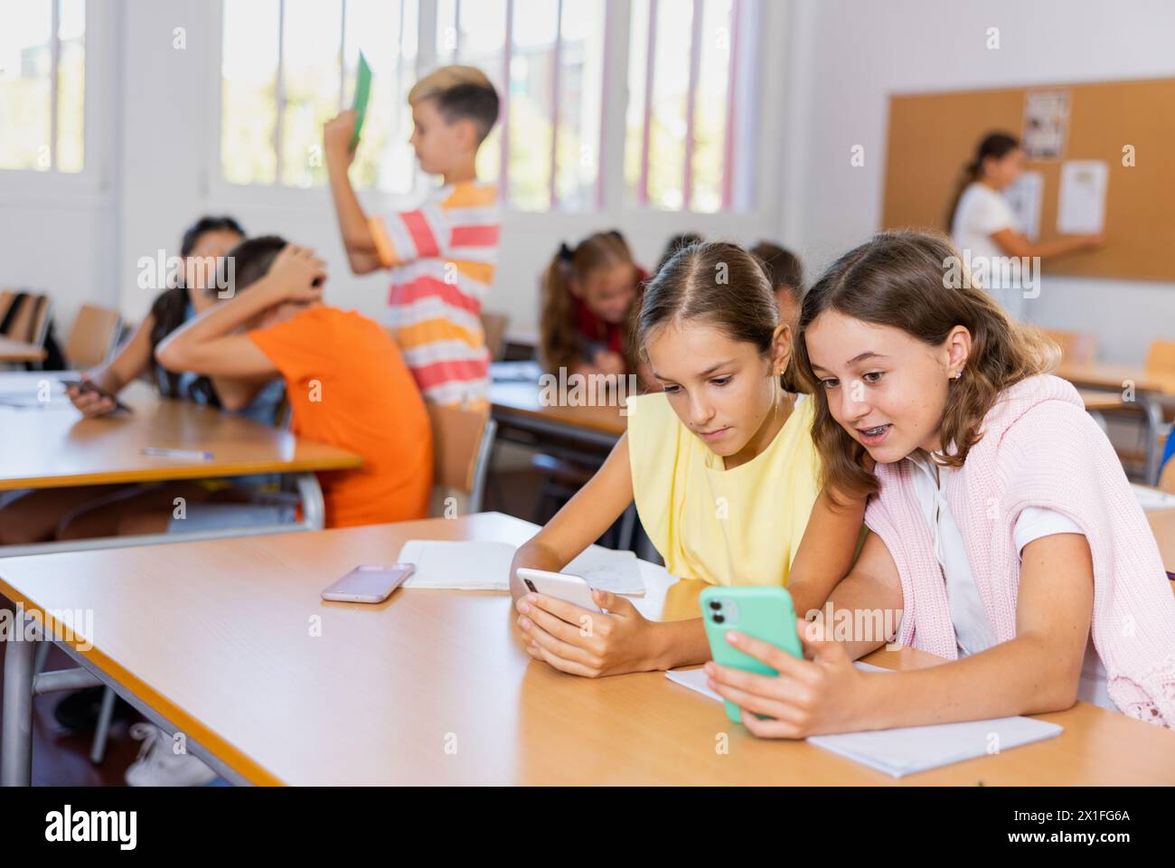 Interested tween students using mobile phones at lesson Stock Photo - Alamy
