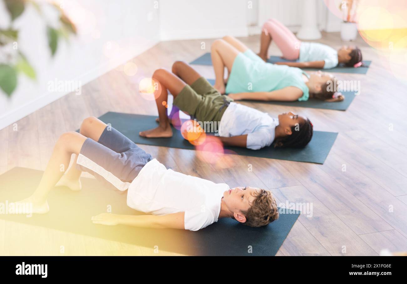 Girls and boys doing abdominal crunches with outstretched arms to ...