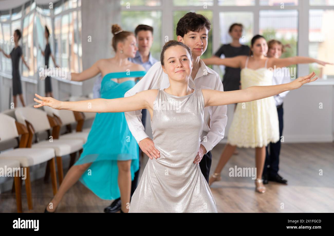 Adolescent ballroom dancers practicing elegant dance moves in pairs ...