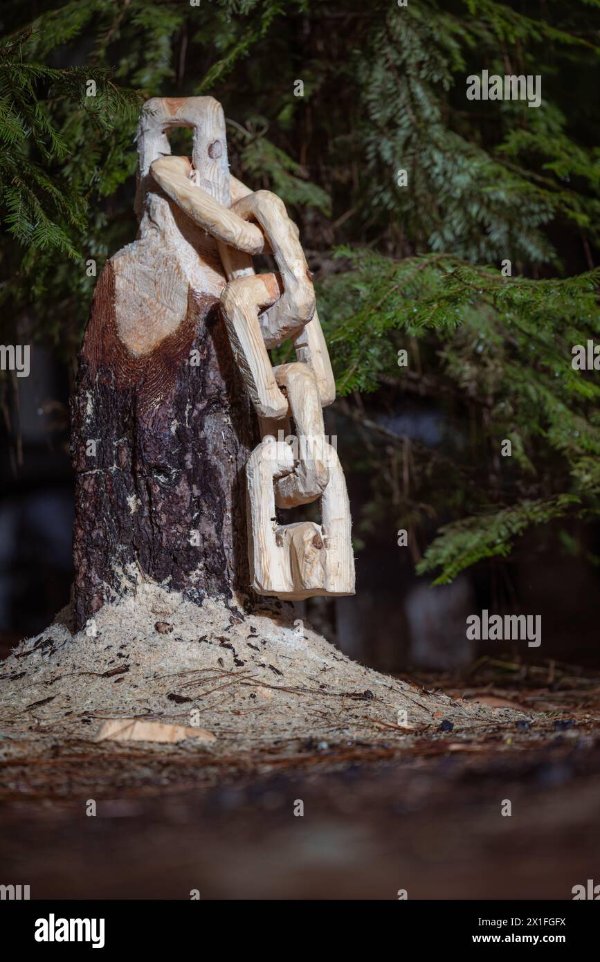 A chain is carved from a tree stump with saw dust on the ground. The ...
