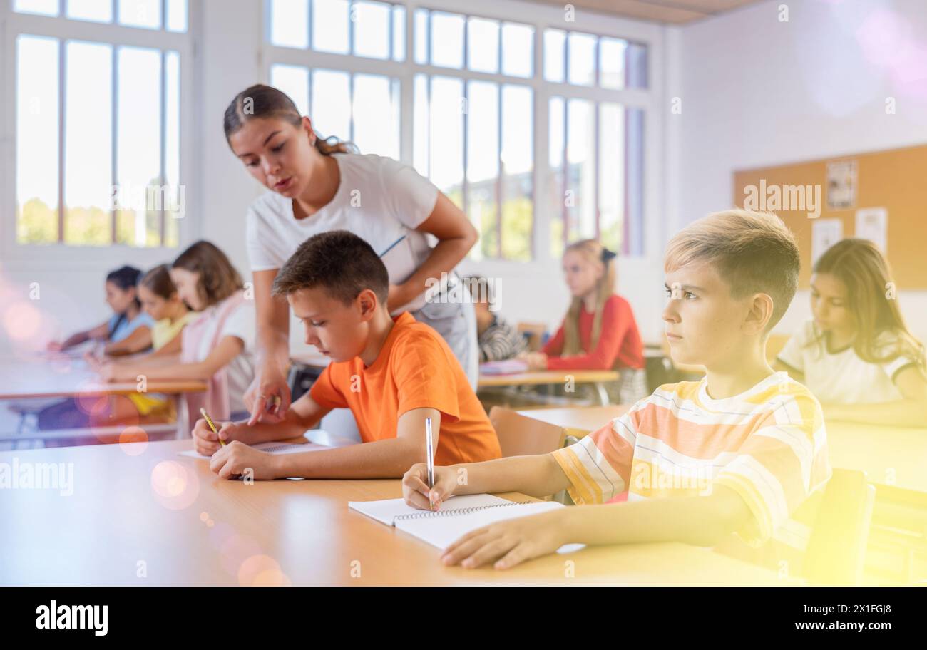 Preteen pupils studying in classroom with female teacher Stock Photo ...