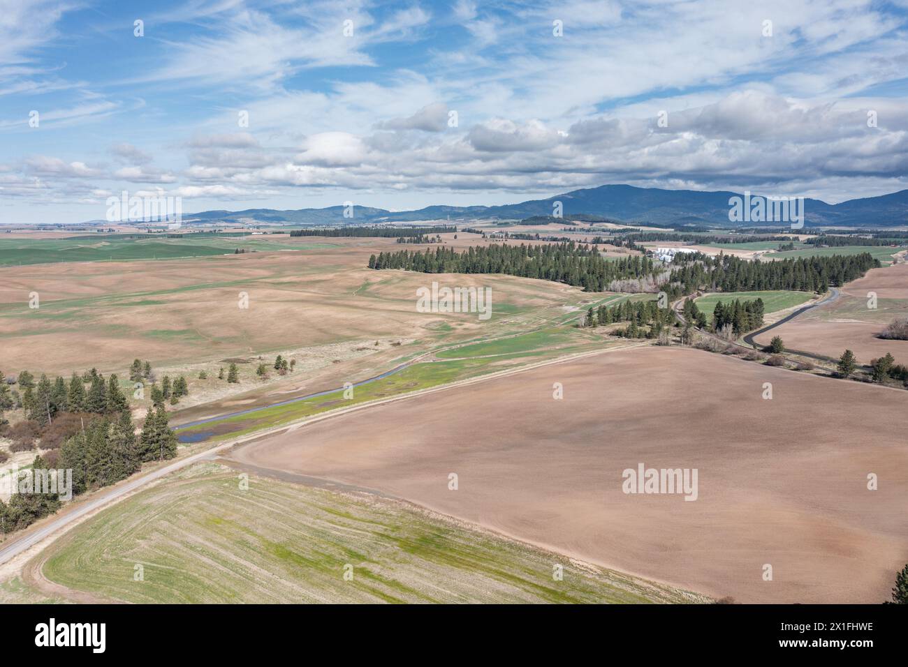 A large, open field with a road running through it. The sky is clear ...