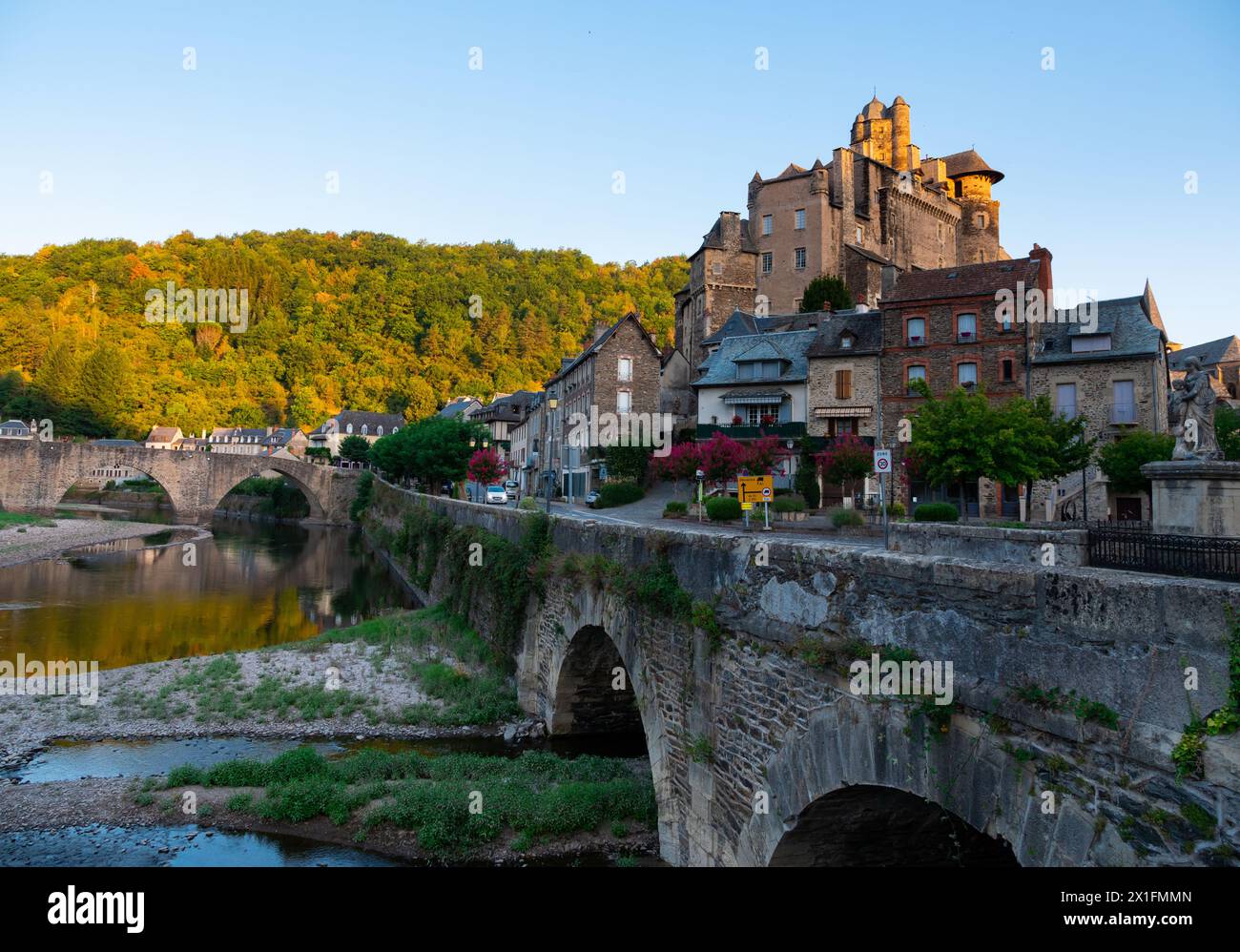 French township of Estaing on bank of Lot River with arched bridge and ...