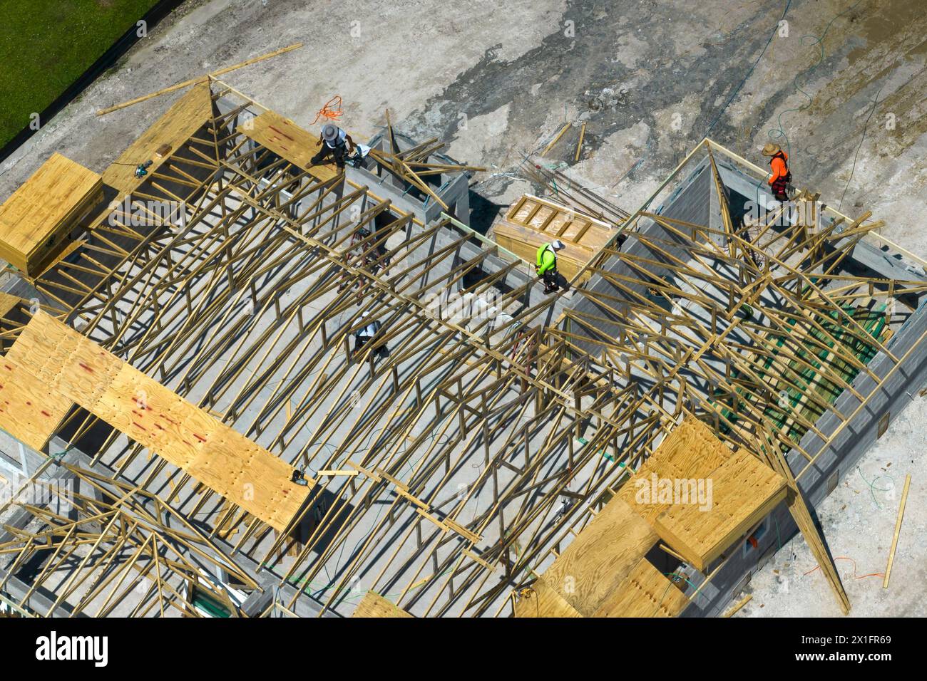 Aerial view of builders working on unfinished residential house with ...