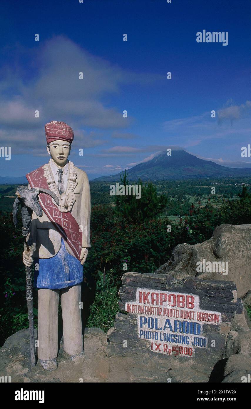 Statue for photographs, with volcano in distance, Mount Sinabung, taken ...
