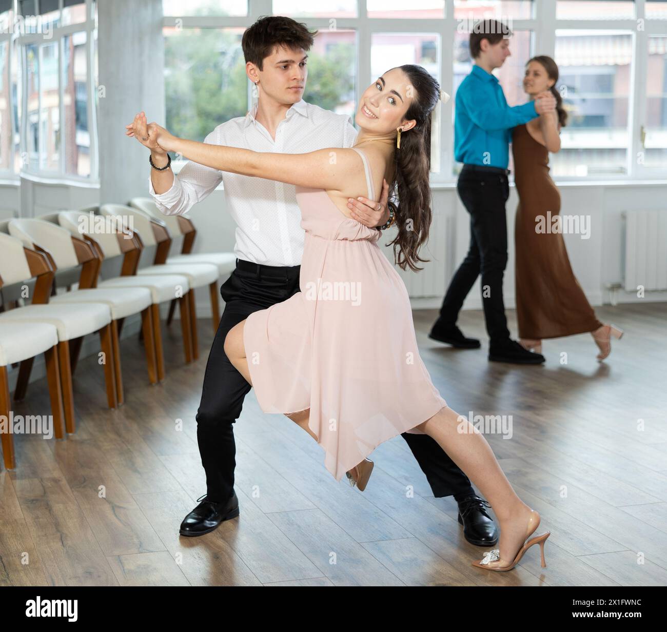 Couple in evening dresses enjoys pair dance tango, interacting with ...