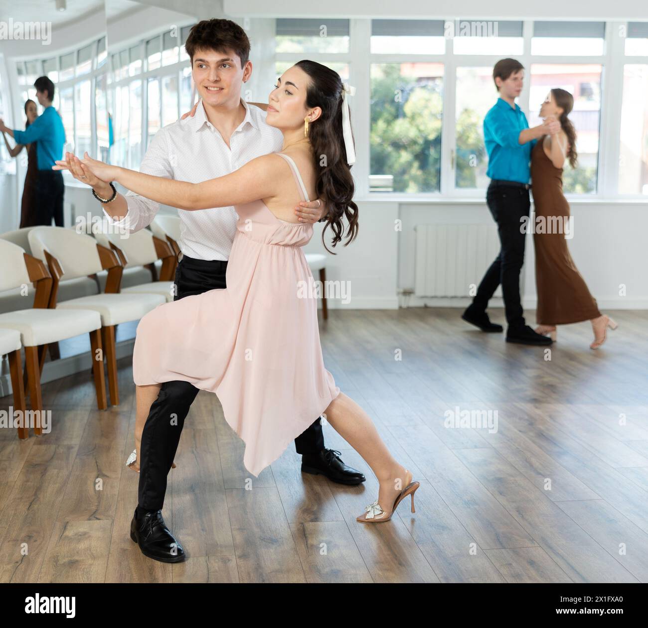 Couple in evening dresses enjoys pair dance tango, interacting with ...