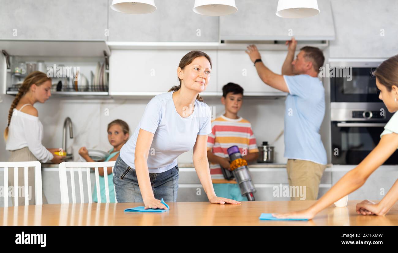 Daughters with mom wipe table, dad and brother do kitchen household ...