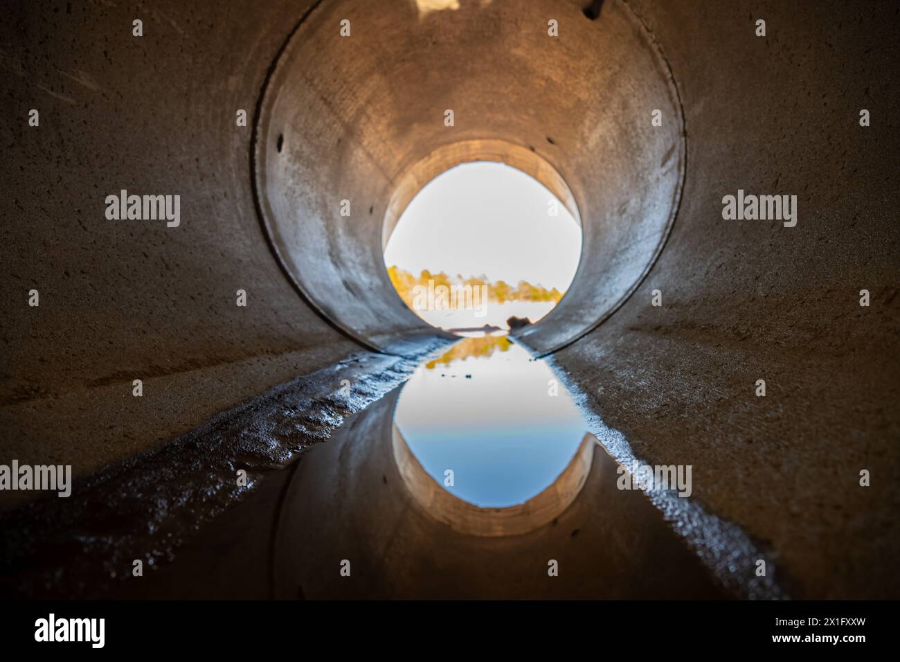 Inside a circular concrete drainage culvert with a trickle of water ...