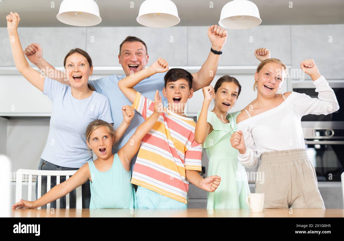 Big friendly family is rejoicing with happiness and raising their hands ...