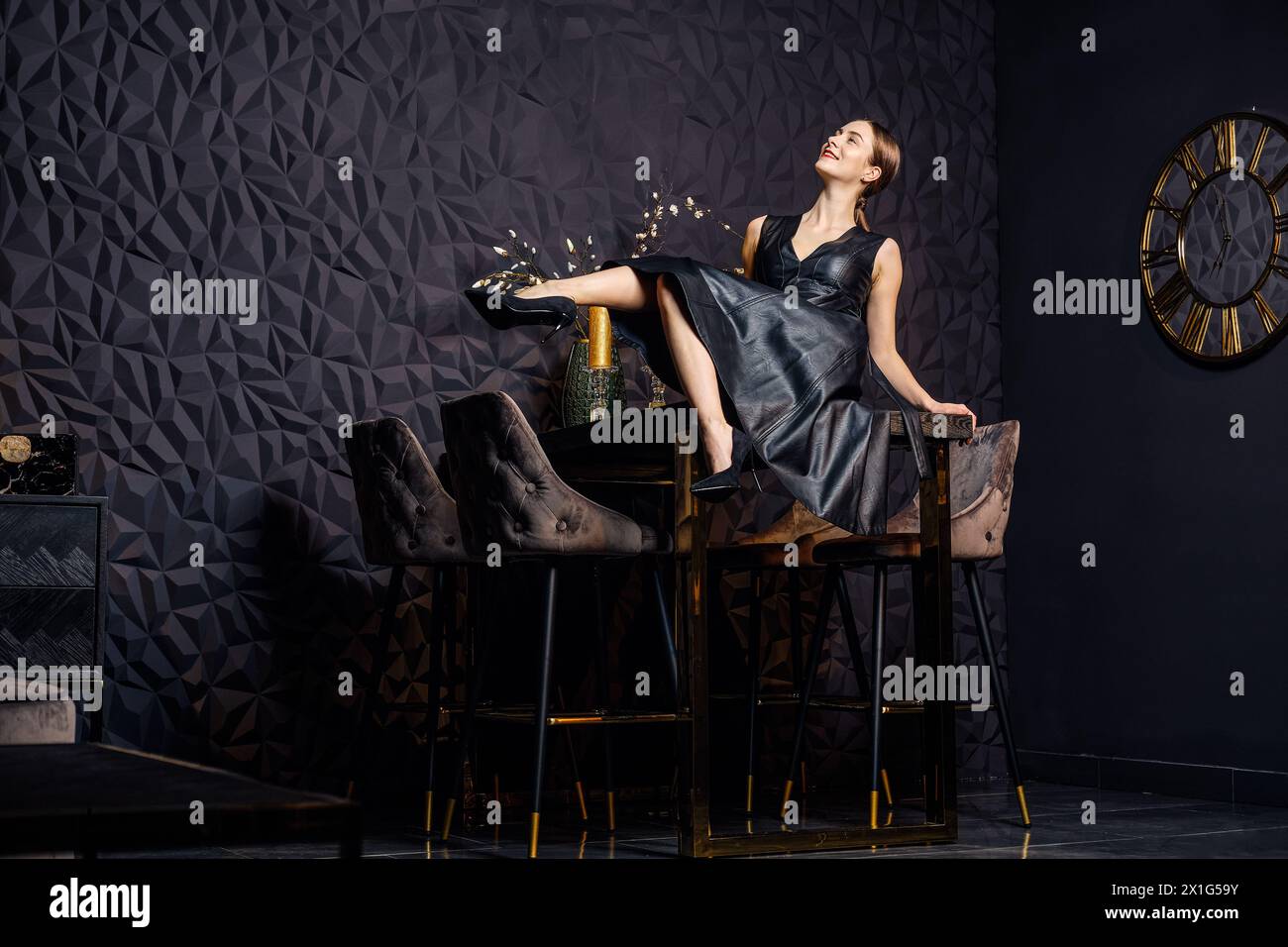 Girl having fun and swings her legs at home sitting on bar table Stock ...