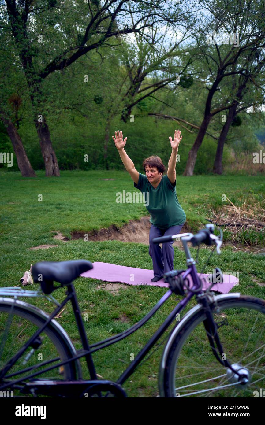 an old woman practices yoga in the morning on the river bank, came from ...