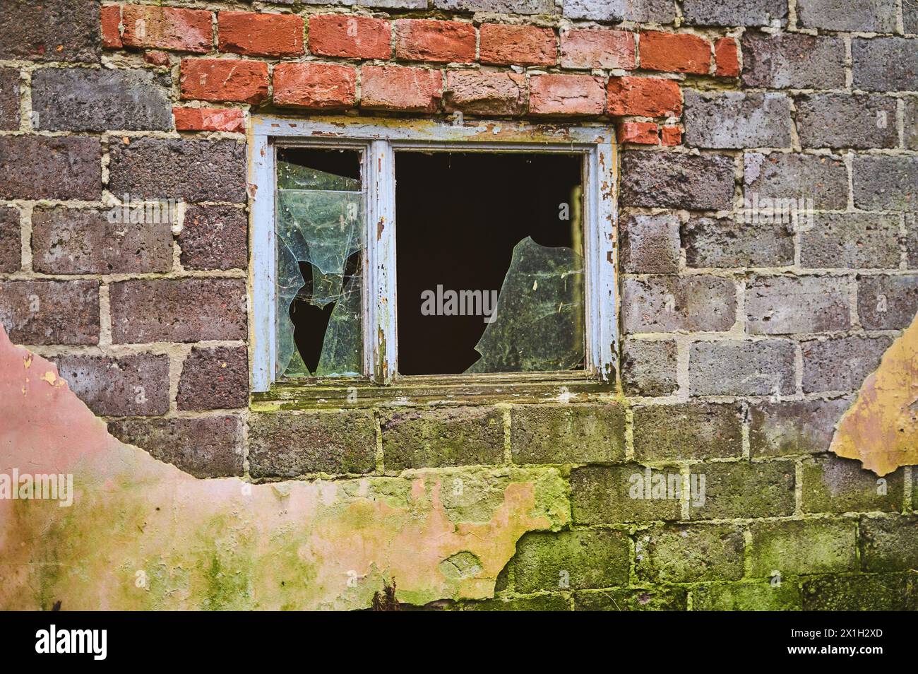 A shattered window in a decaying cinder block structure tells tales of ...