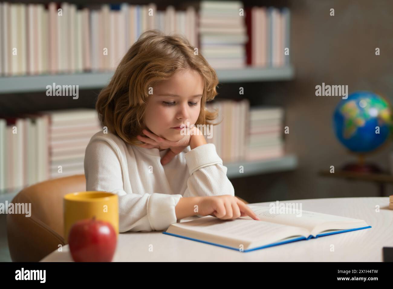 Back to school. School child studying in school library. Kid reading ...
