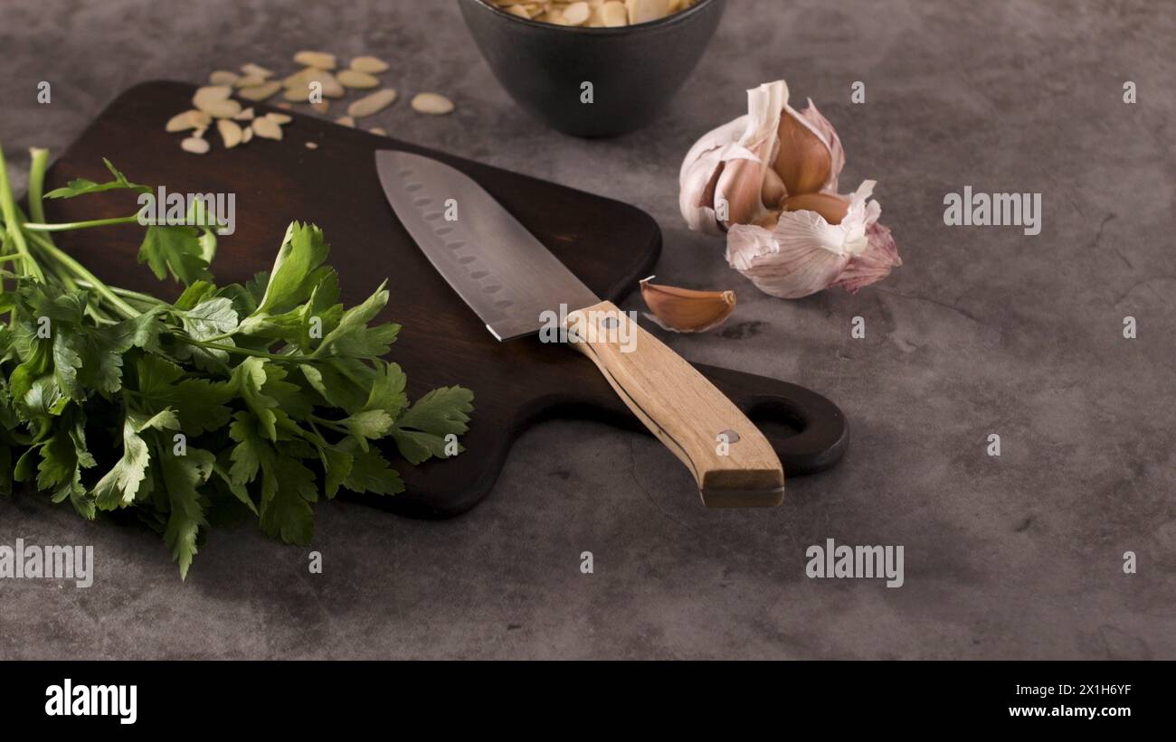 Fresh garden herbs on kitchen countertop. Parsley, garlic, knife and ...
