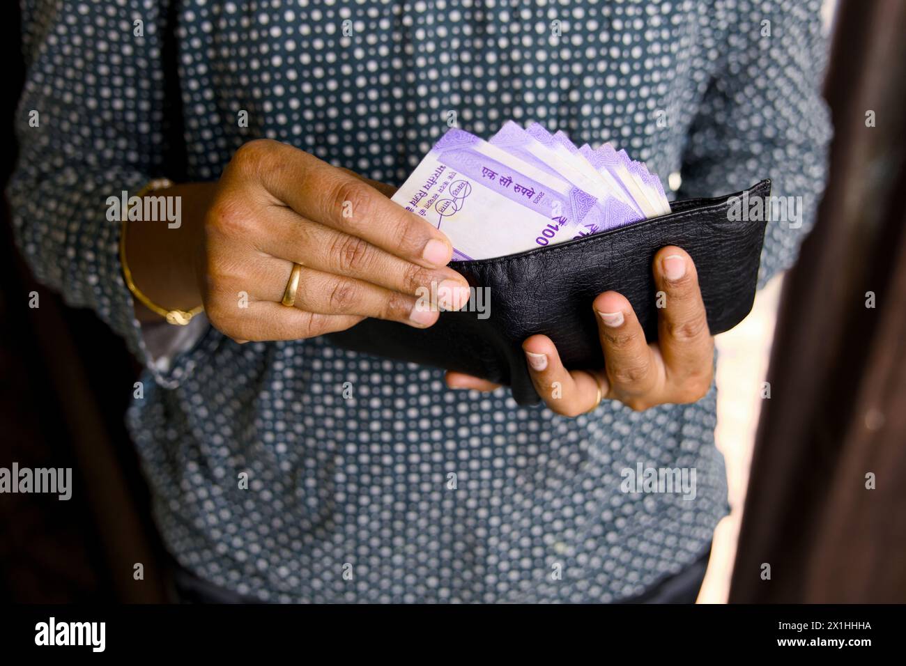 This image is about woman holding a wallet full of hundred Indian rupee ...