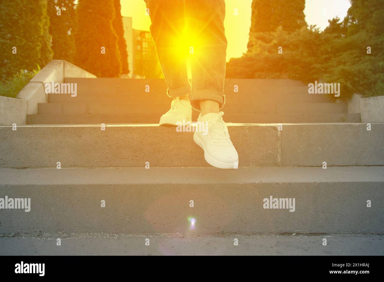 Female legs in white summer sneakers and rolled up jeans descending the ...