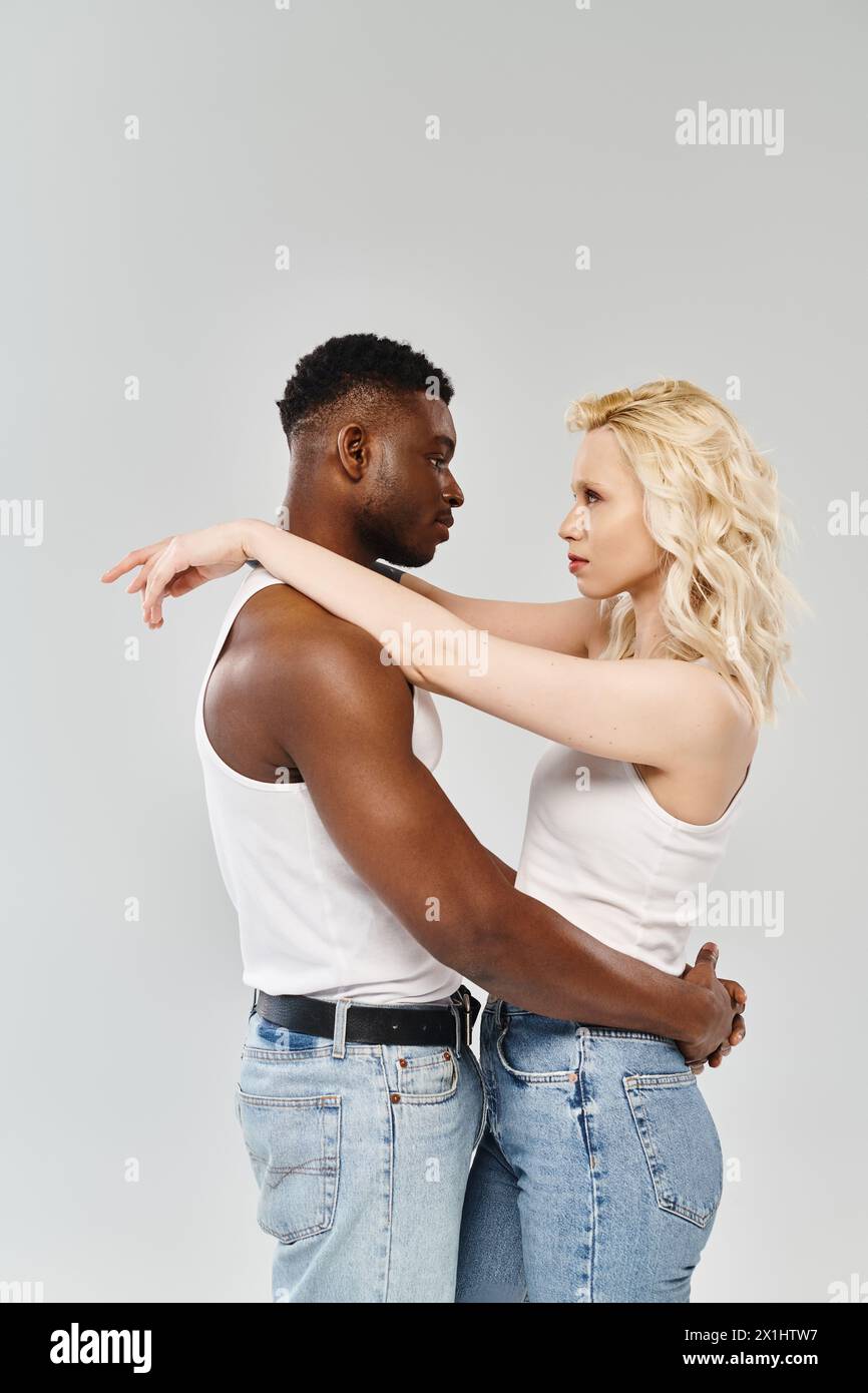 A young multicultural couple standing together on a grey background ...