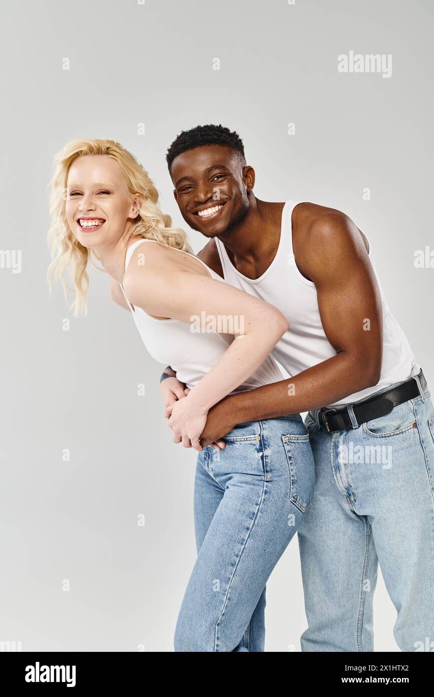 A young multicultural couple strikes a dynamic pose in a studio against ...