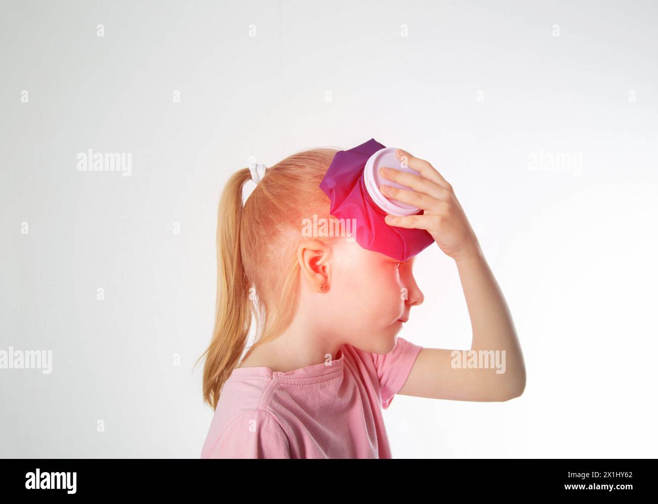 A little girl holds a bag of ice cold against her head. The concept of ...