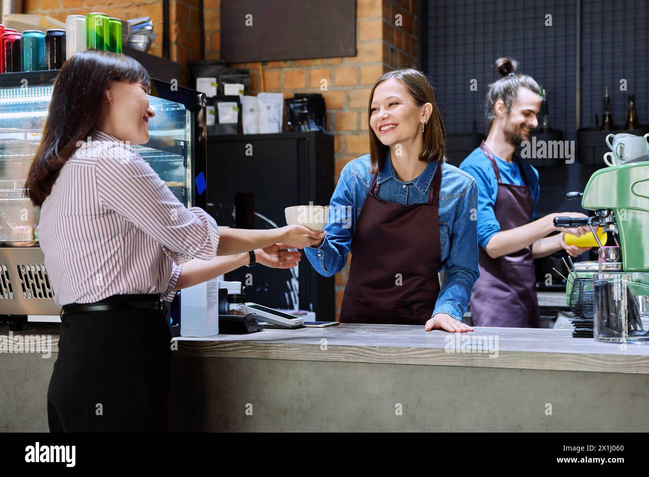 Woman customer of coffee shop near counter with cup of coffee talking ...