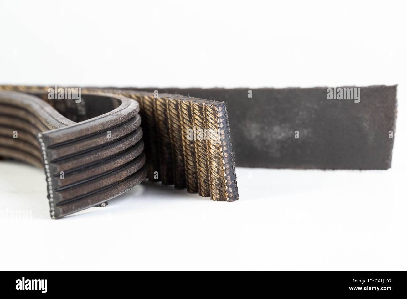 Torn timing belt and generator rivulet belt on a white background ...