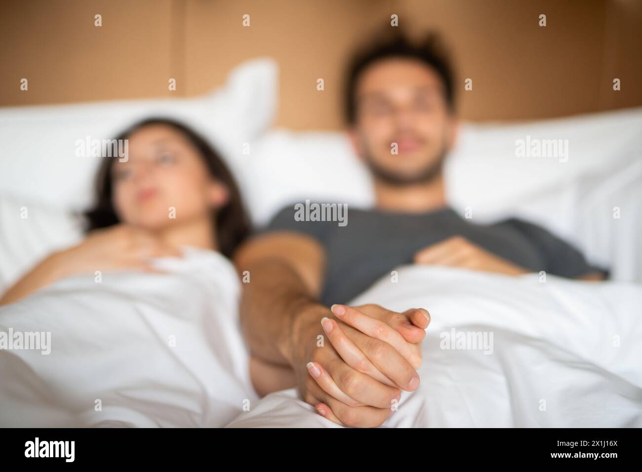 Young couple holding their hands in bed Stock Photo - Alamy