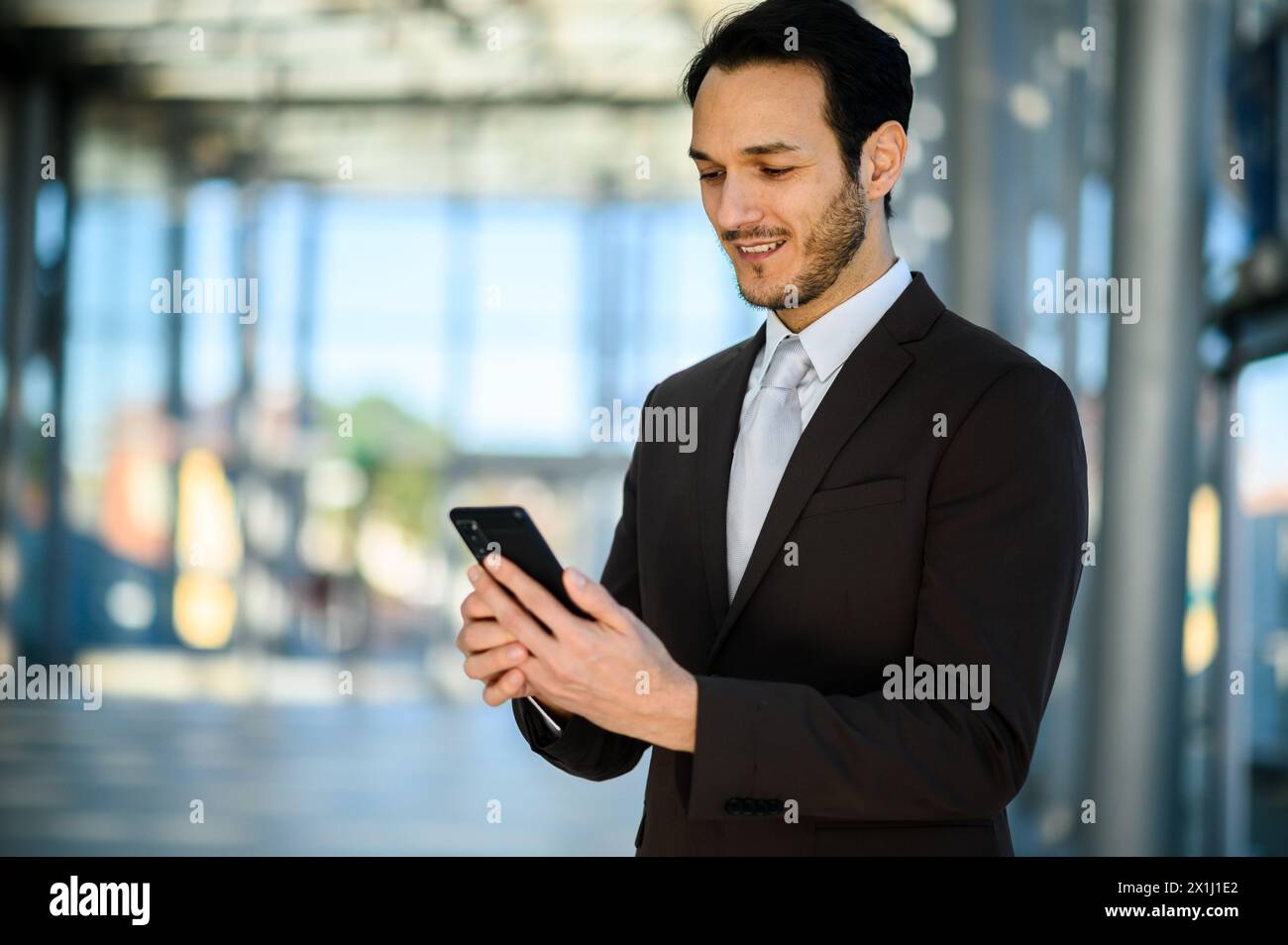 Young professional businessman smiling while using smartphone to check ...