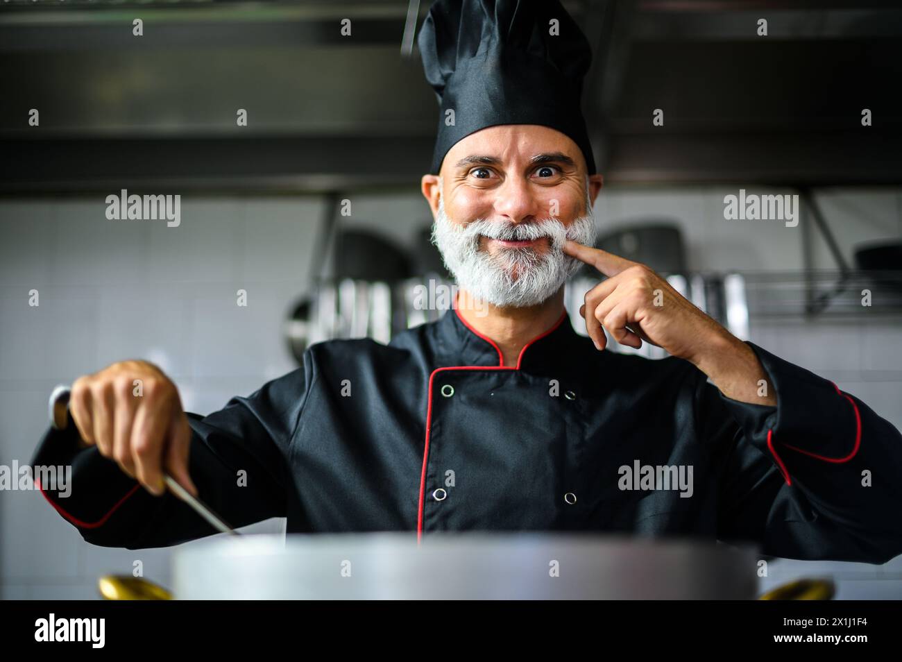 Happy male chef in uniform and hat with a playful expression while ...
