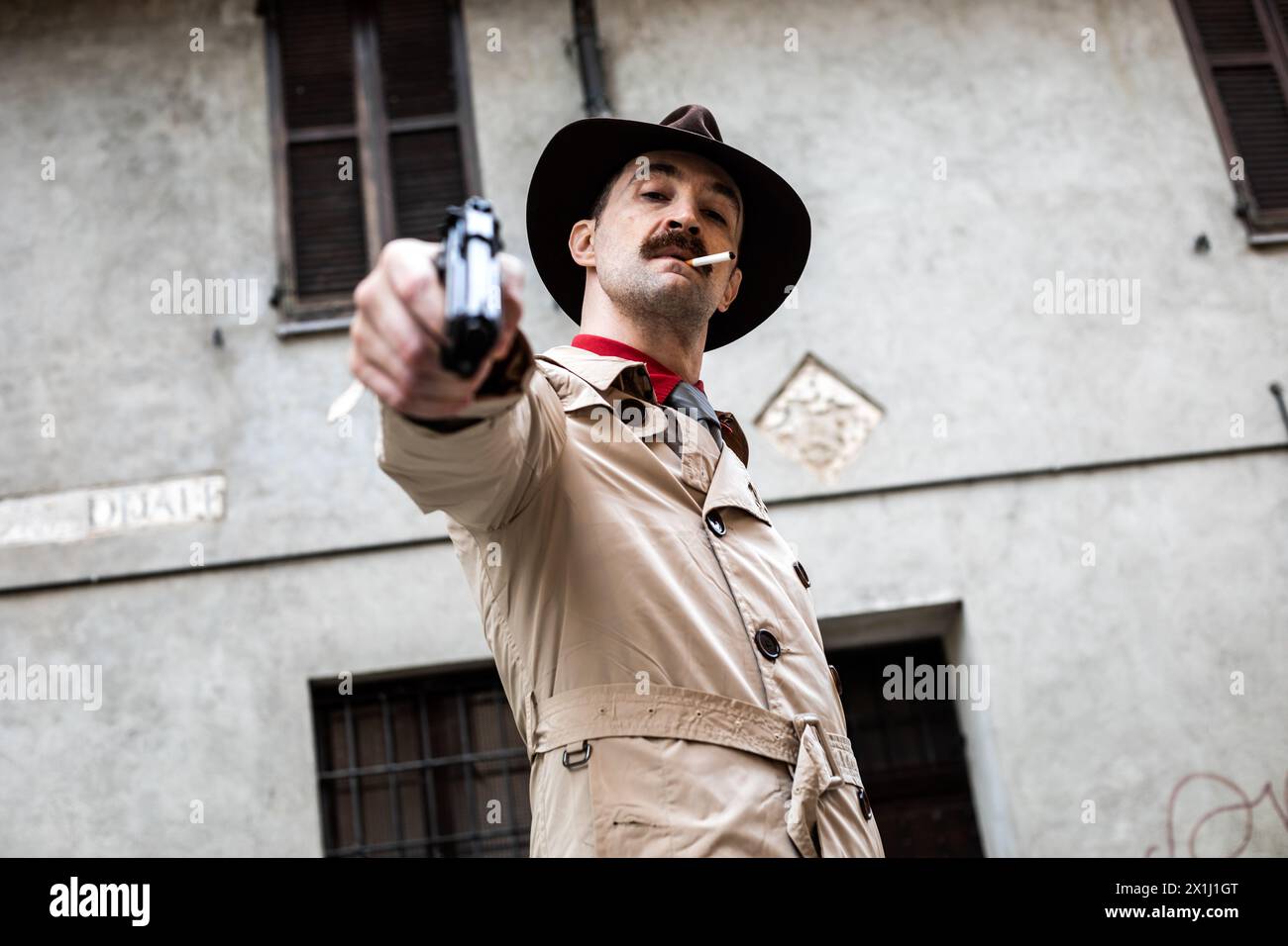 Vintage dressed detective character holding a gun with serious ...