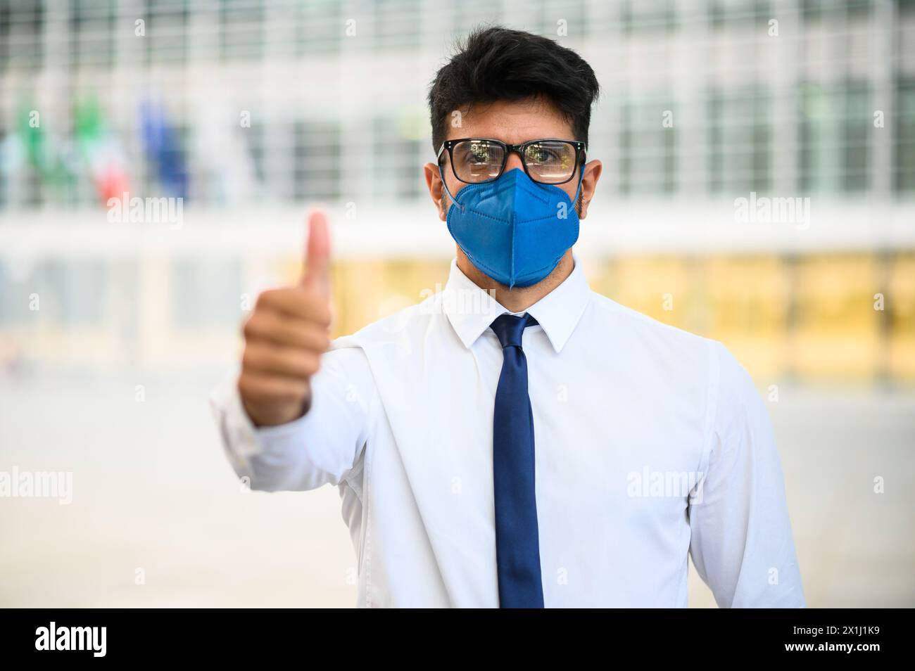 Young businessman outdoor in a modern setting giving thumbs up and ...