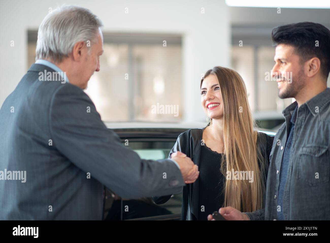 Car dealer giving an handshake and giving keys to seal the deal for new ...