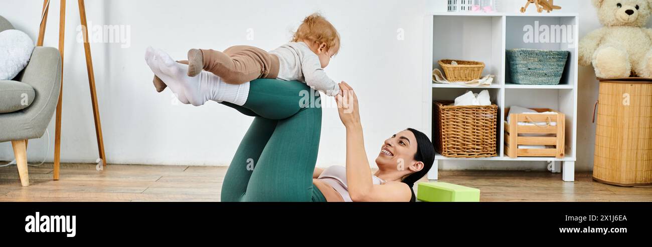 A young, beautiful mother joyfully lifts her baby up in the air while ...