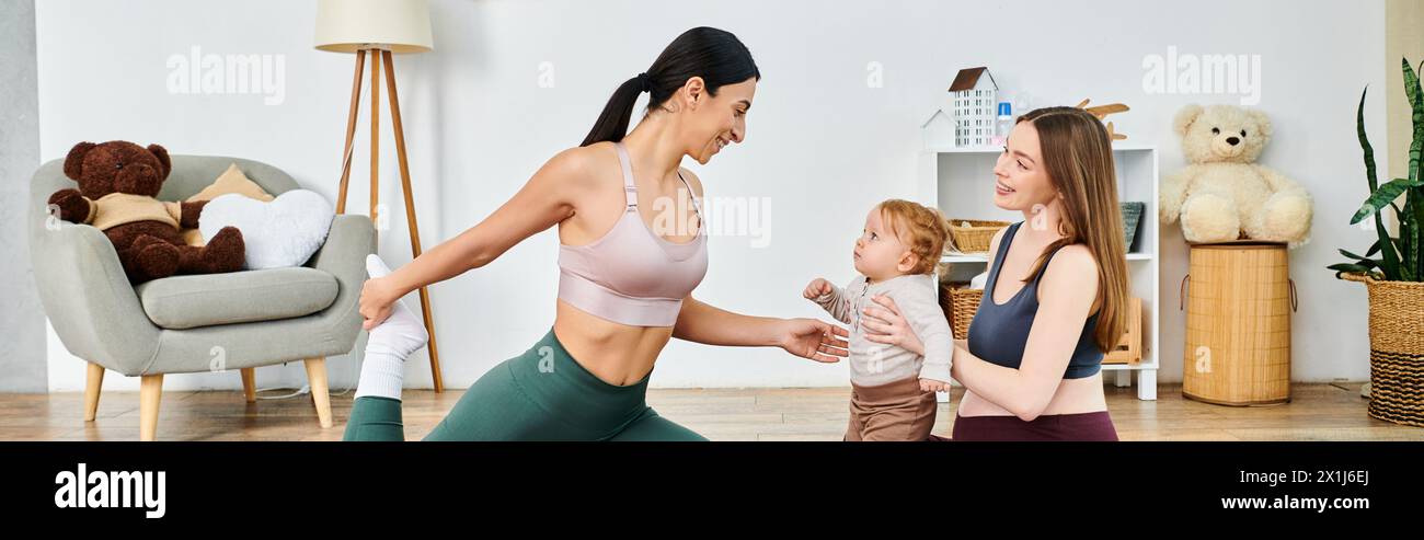 A beautiful young mother in a sports bra and leggings joyfully dances with a toddler at home ...