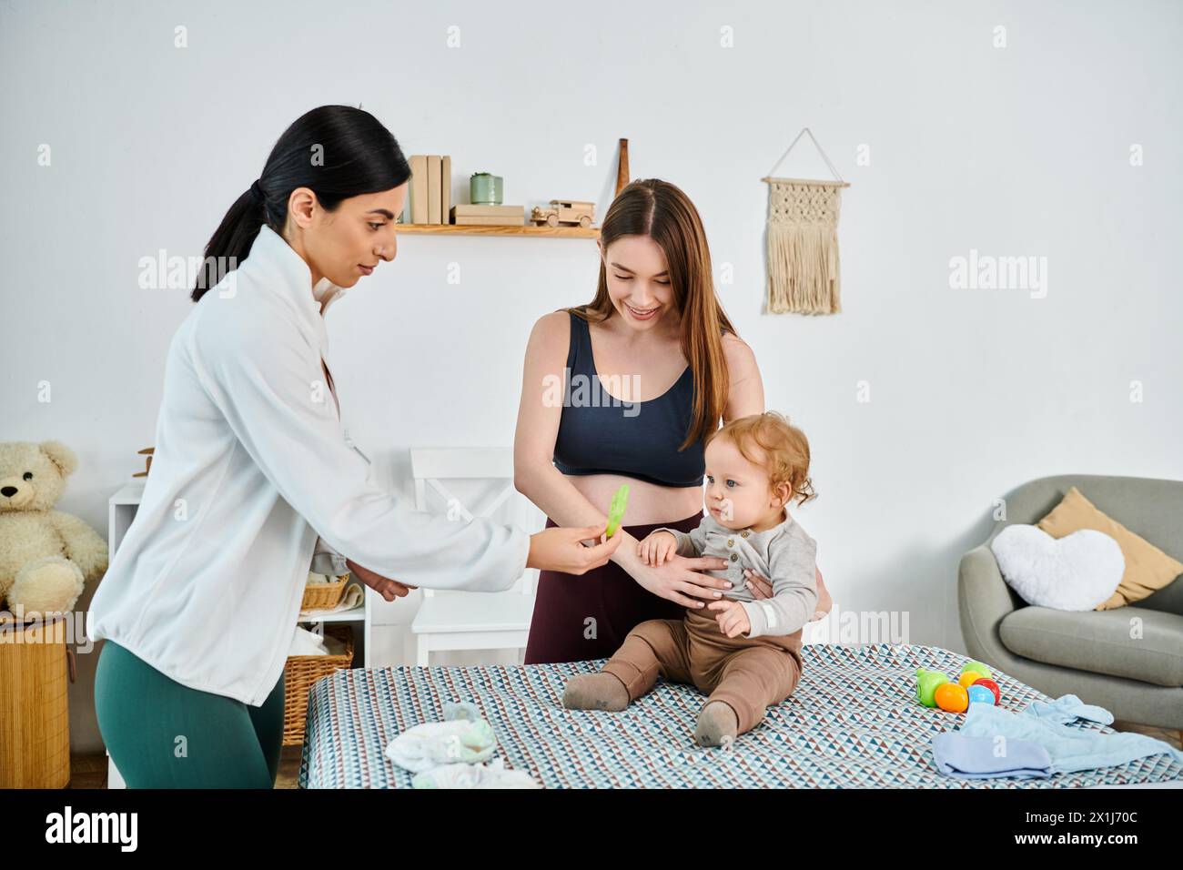 A young, beautiful mother lovingly cradles her baby in her lap, while ...