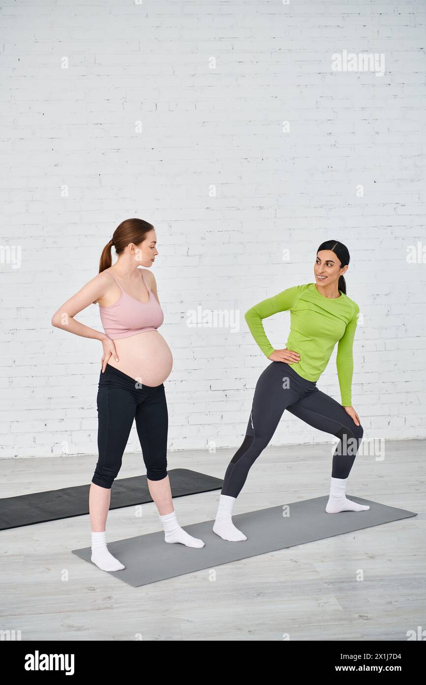 Two pregnant women standing side by side, one coaching the other during ...