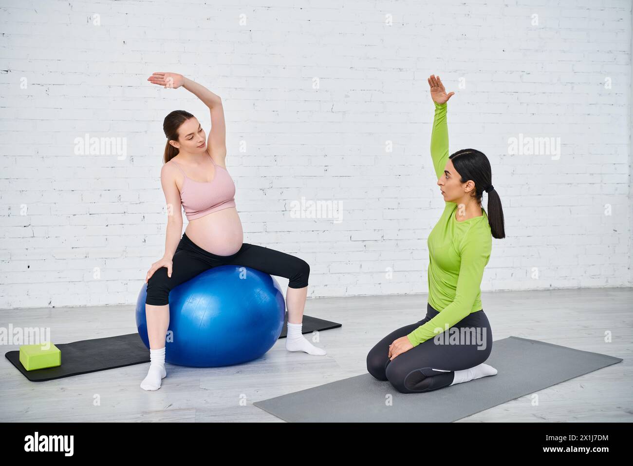 pregnant woman follow her coach, exercising yoga poses on exercise ...