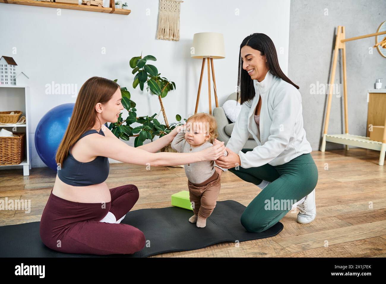 A young beautiful mother lovingly cradles her baby in her lap ...
