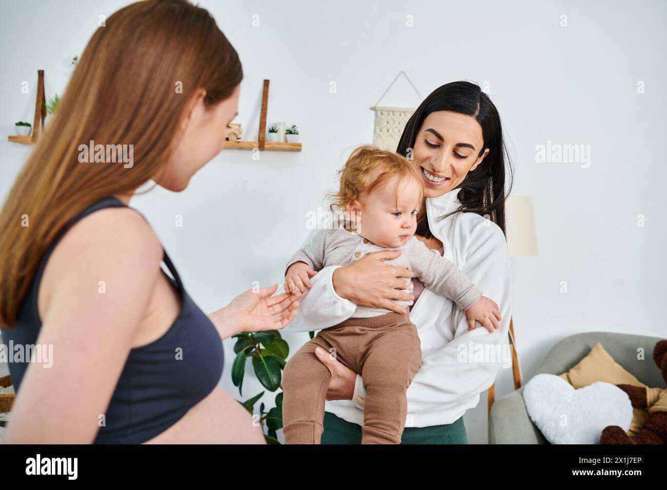 A young beautiful mother lovingly holds her baby in her arms, supported ...