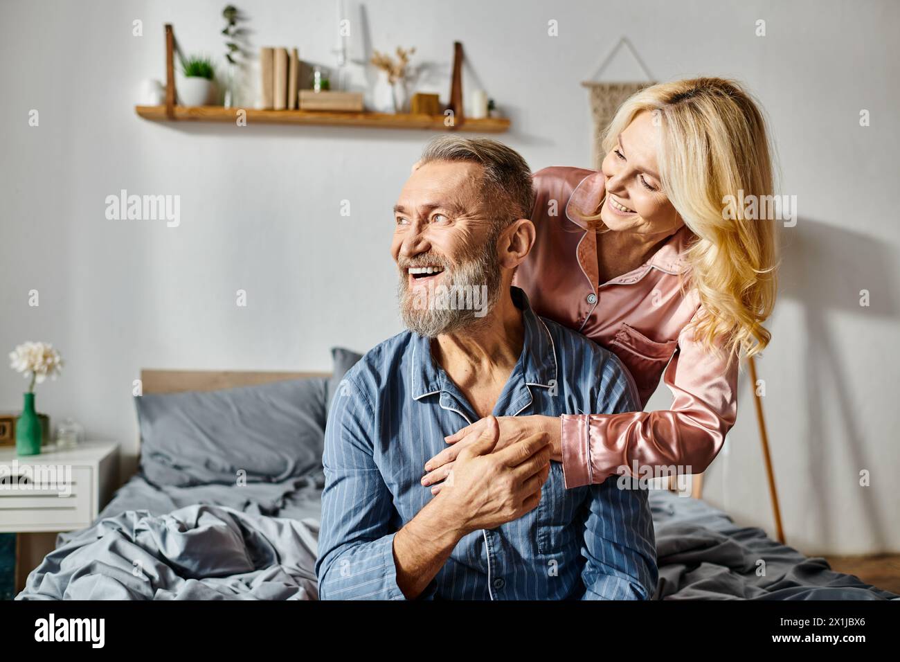 A man carrying a woman on his back in a cozy bedroom setting, showing ...