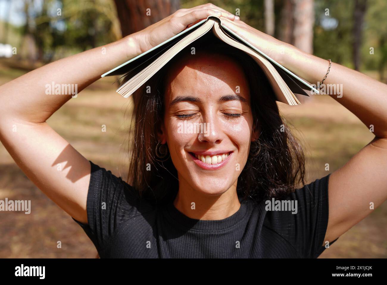 Portrait smiling adult woman with a book above the head. World book day ...