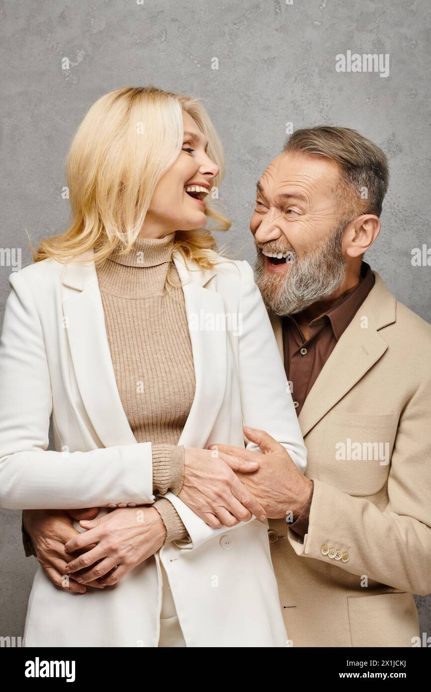 Mature man and woman, elegantly dressed, pose next to each other in a ...