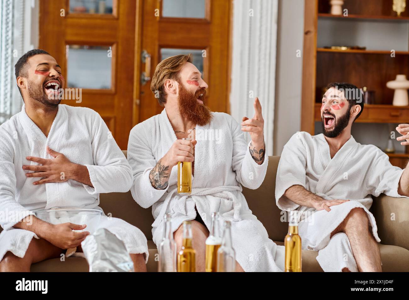 Three diverse, cheerful men in bathrobes sitting atop a couch, enjoying ...