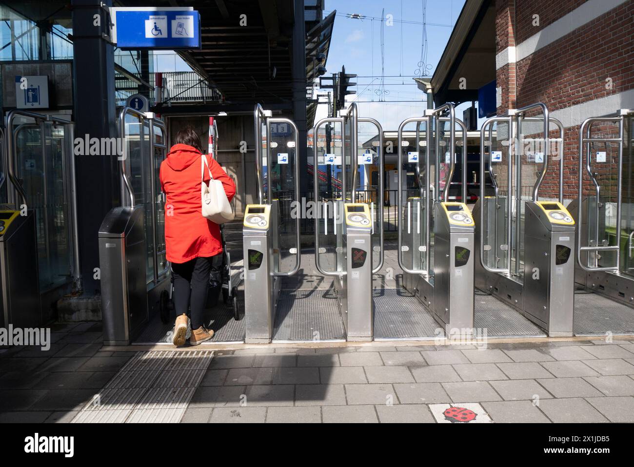 Woman with pushchair using electronic gate to enter Hoorn Railway ...